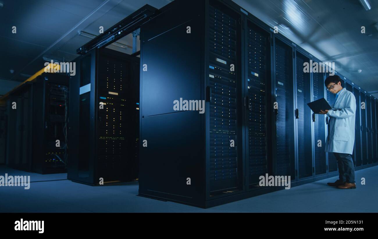 In Data Center: Male IT Specialist Wearing White Coat Stands Beside ...