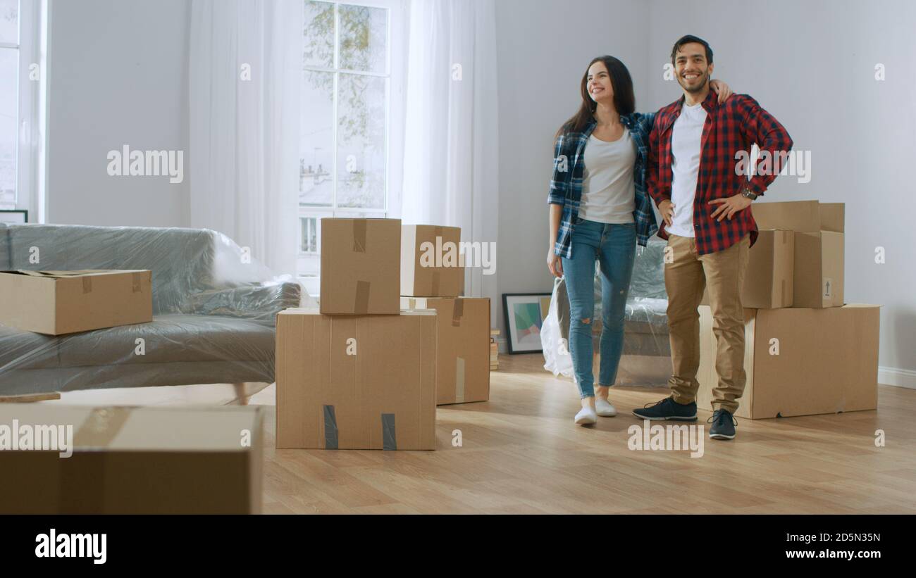 Happy Young Couple Moving Into New Apartment, Carrying Cardboard Boxes ...