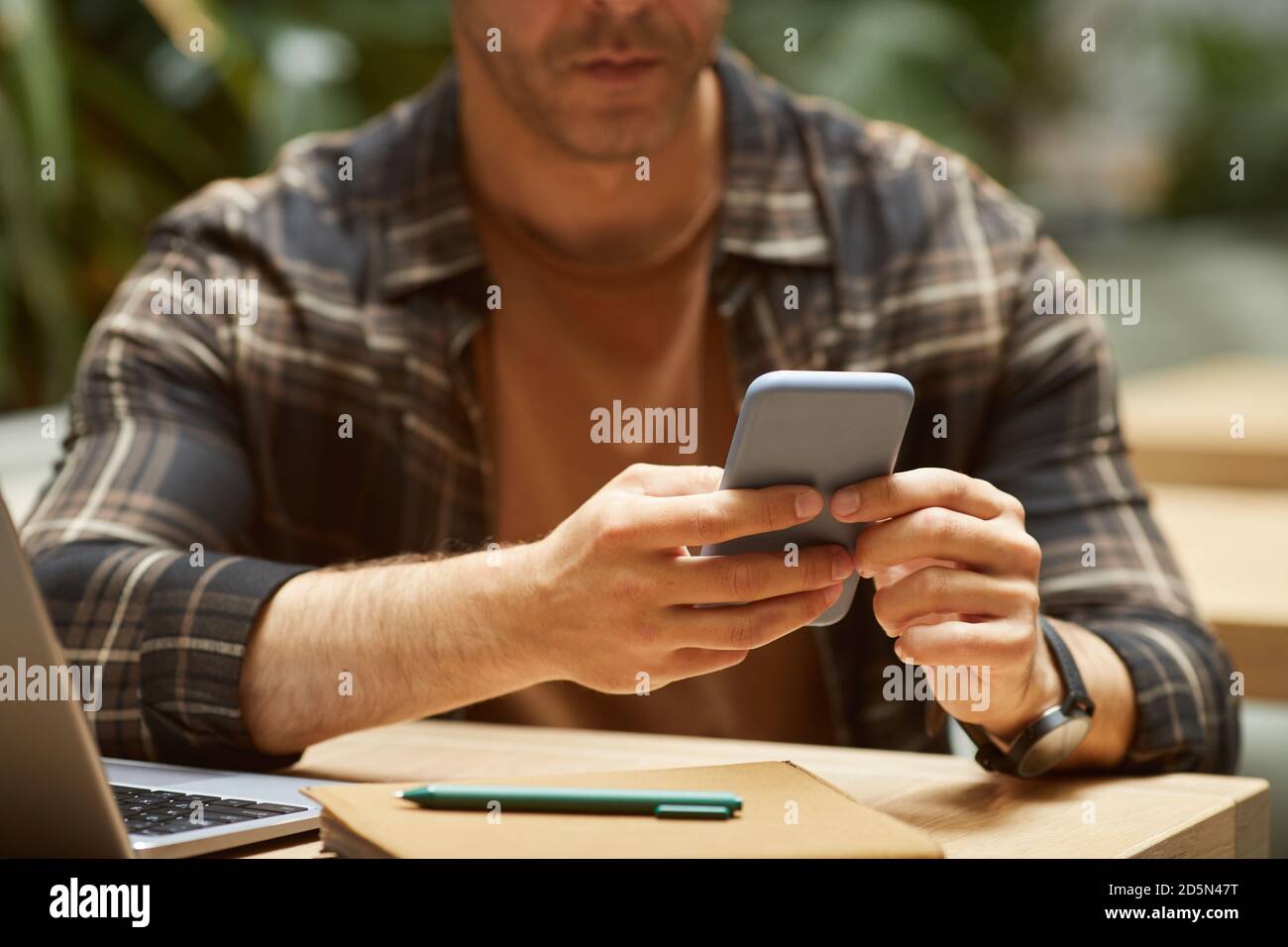 Close-up of man typing a message on mobile phone while working at the ...