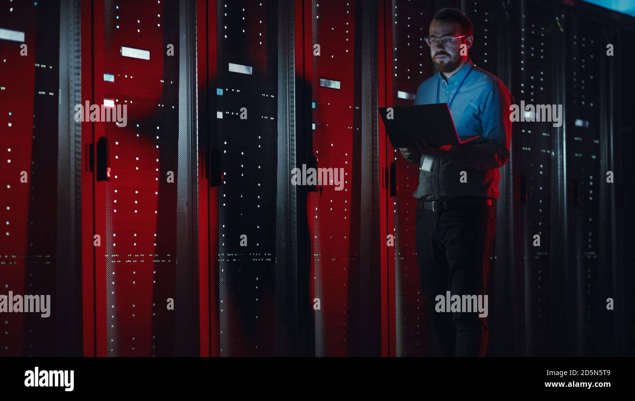 Bearded IT Specialist in Glasses is Working on Laptop in Data Center ...