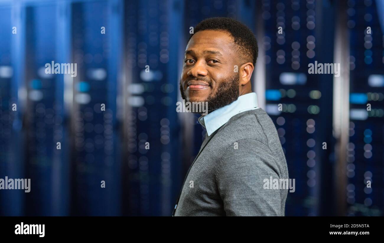 Young Black Data Center IT Technician Standing in Server Rack Corridor ...