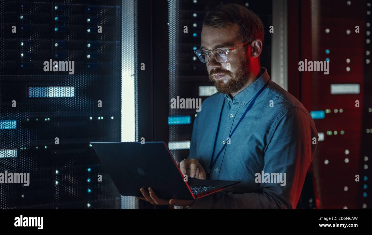Bearded IT Specialist in Glasses is Working on Laptop in Data Center ...