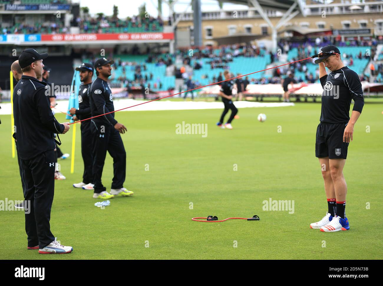 Surrey captain Gareth Batty helps Thomas Curran (right) with his pre ...