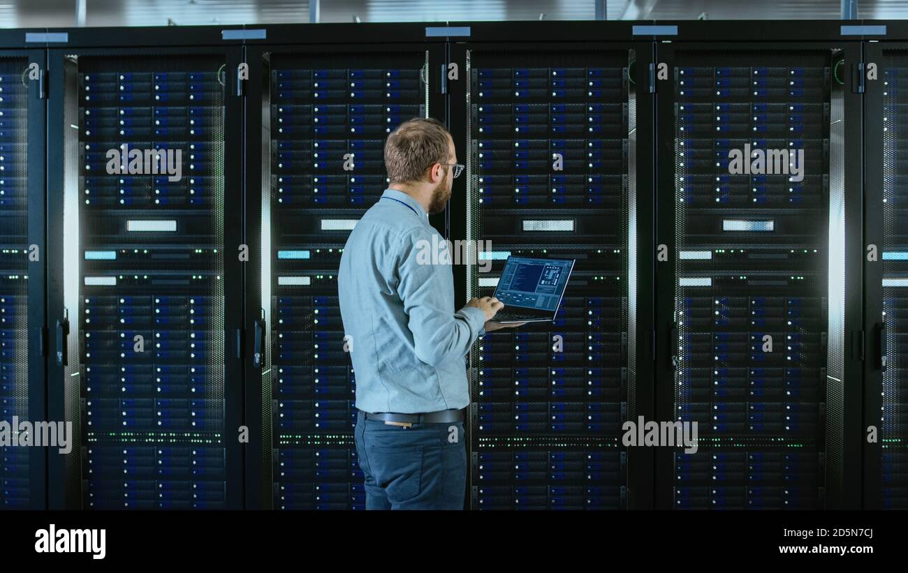 Bearded IT Specialist in Glasses is Working on Laptop in Data Center ...