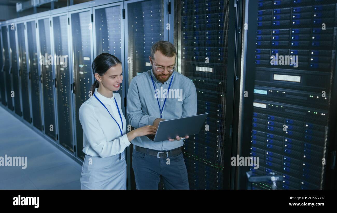 Bearded IT Technician in Glasses with a Laptop Computer and Beautiful ...