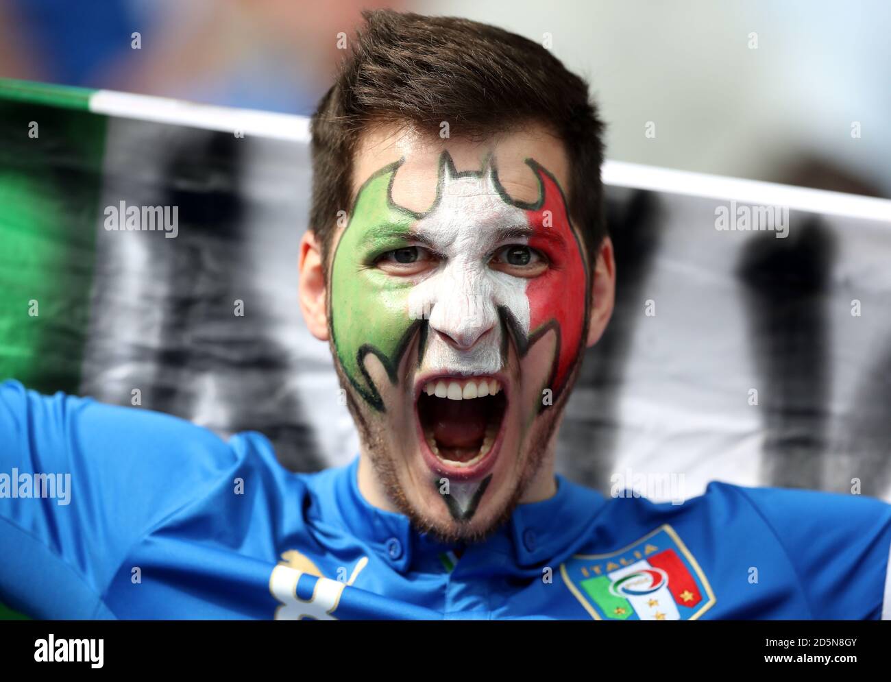A Italy fan with his face painted cheers on his side in the stands ...