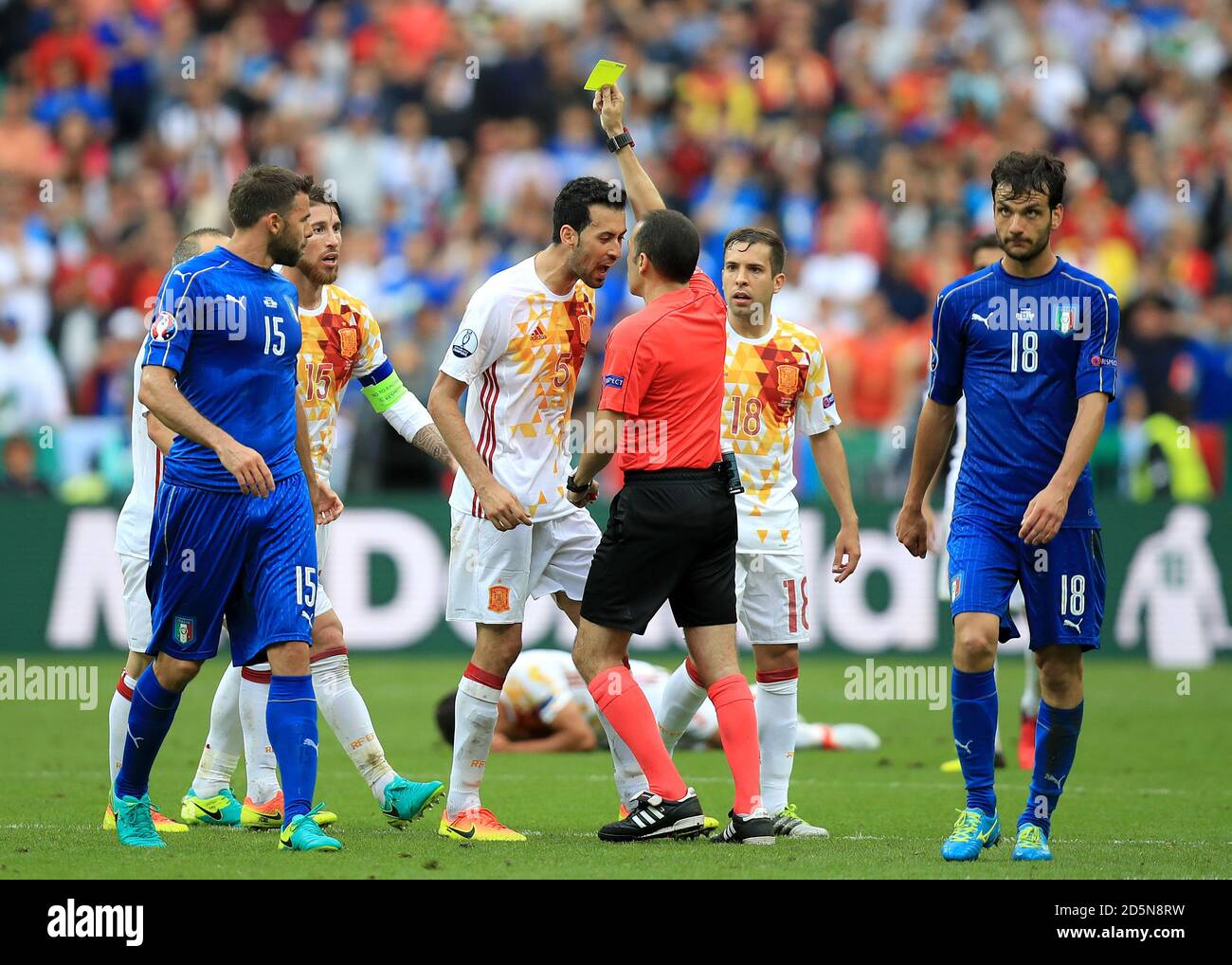 Referee Cuneyt Cakir shows a yellow card to Spain's Sergio Busquets ...