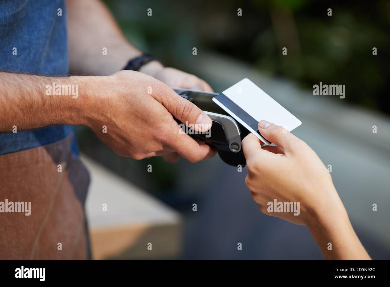 Close-up of waiter holding payment terminal while woman using her ...