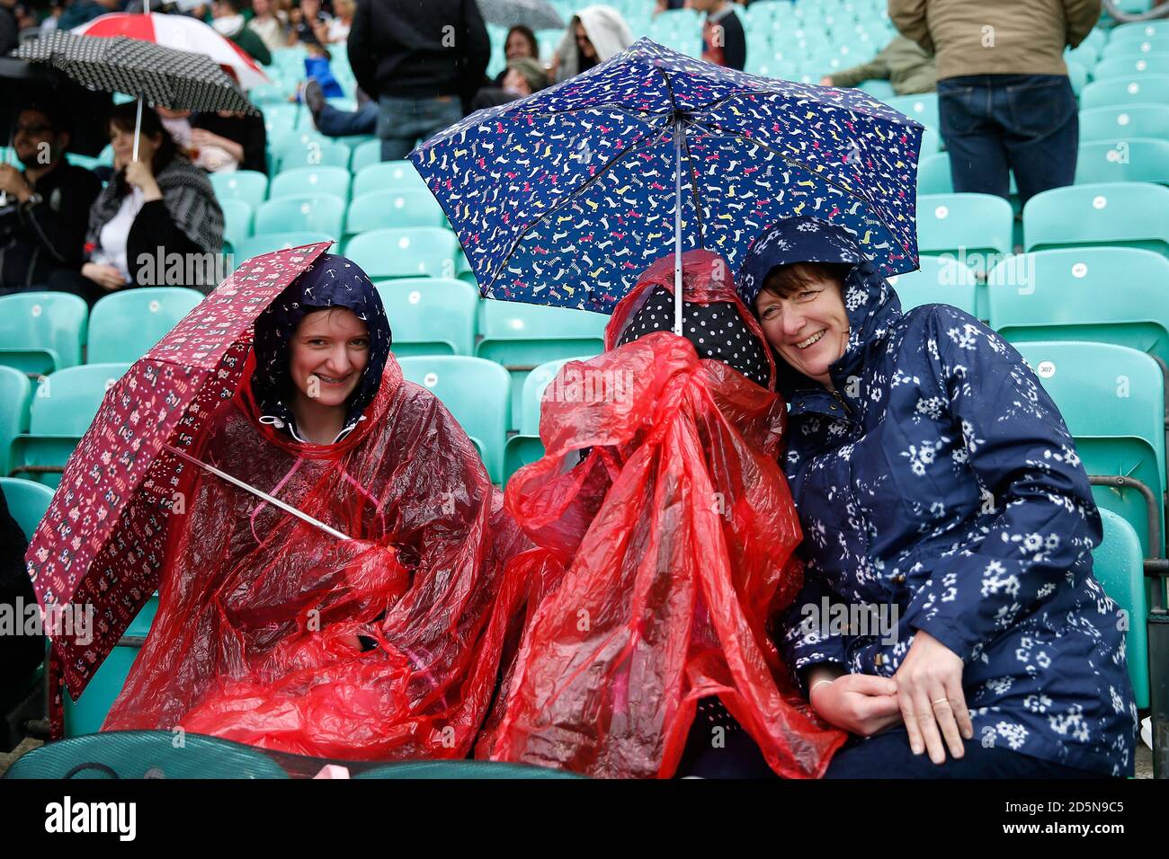 Surrey fans shield from the rain in the stands at the Kia Oval Stock ...