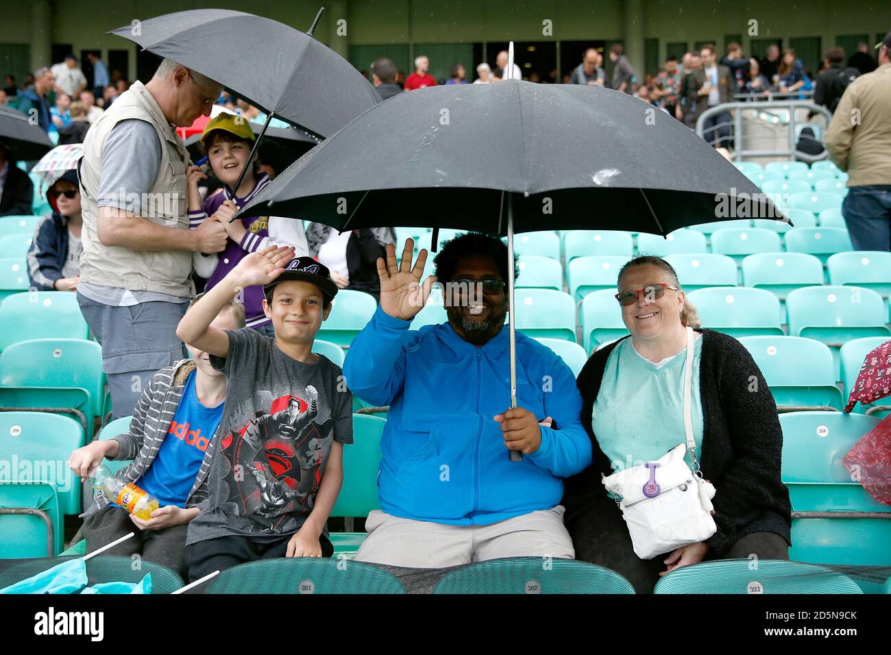 Surrey fans shield from the rain in the stands at the Kia Oval Stock ...