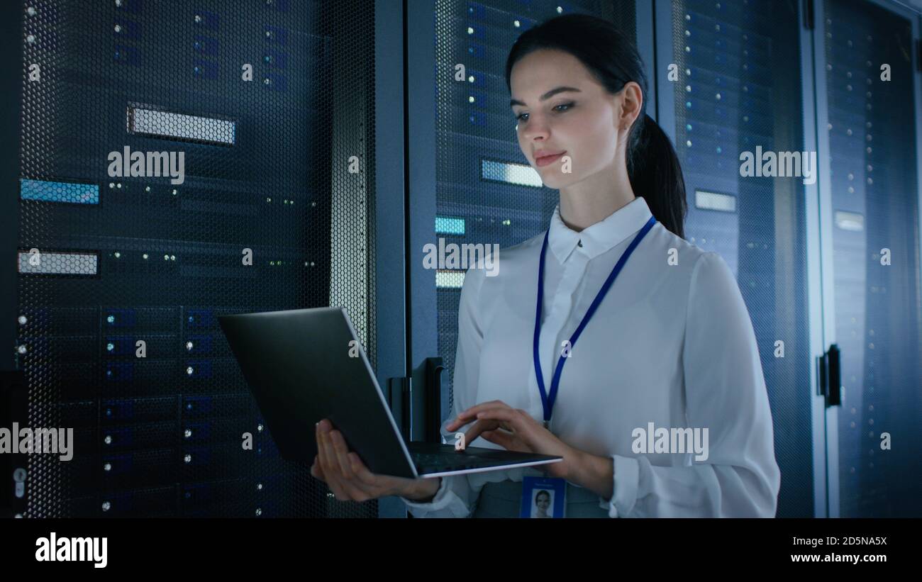 Confident and Beautiful Female IT Engineer is Working on Laptop in Data ...