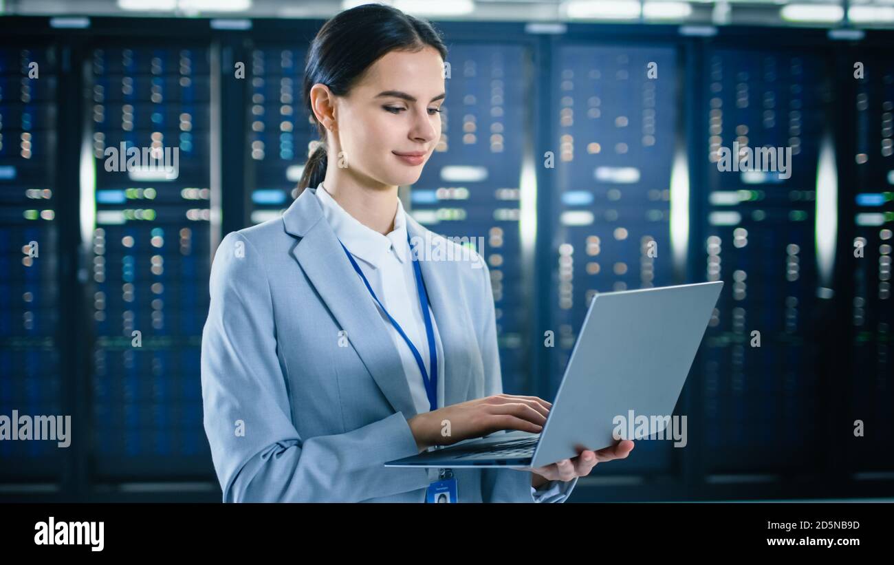 Female IT Specialist is Working on Laptop in Data Center Next to Server ...