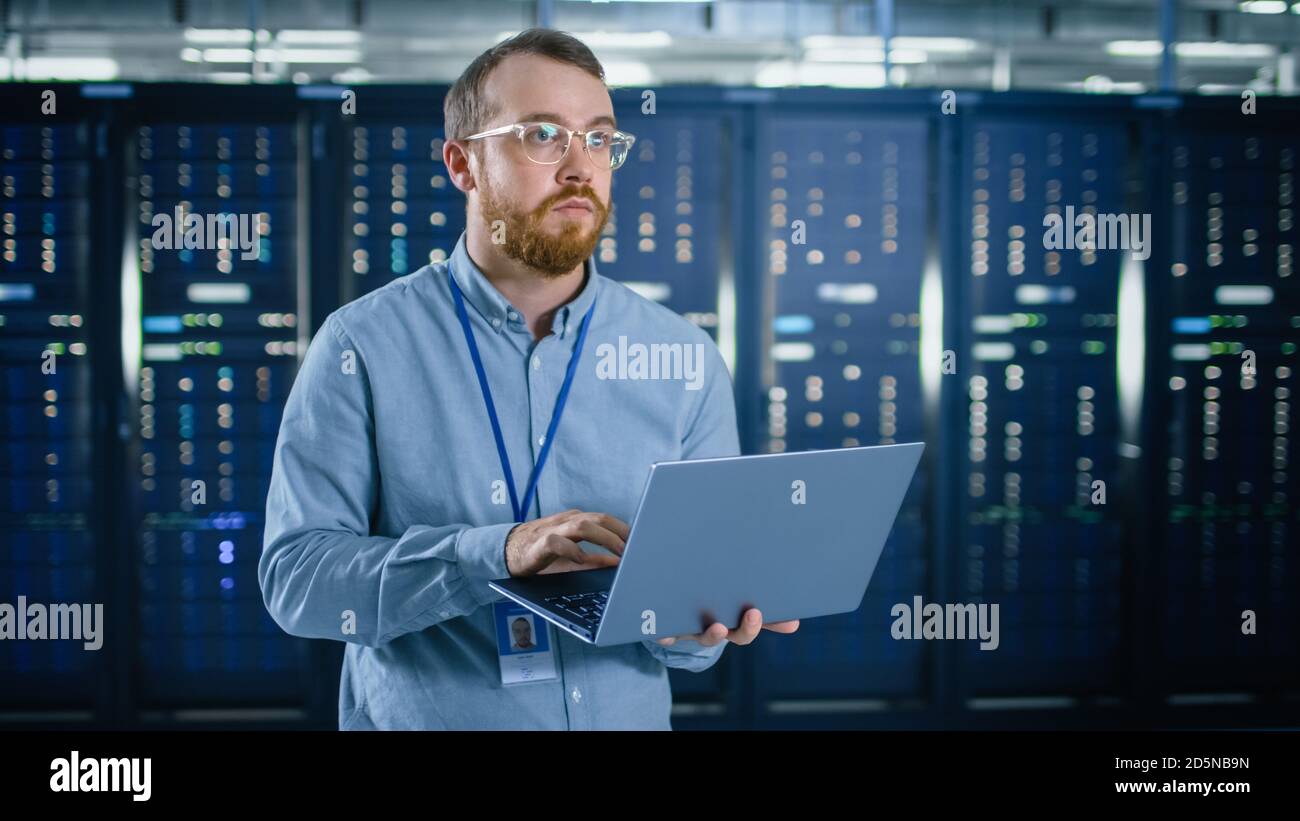 Bearded IT Specialist in Glasses is Working on Laptop in Data Center ...