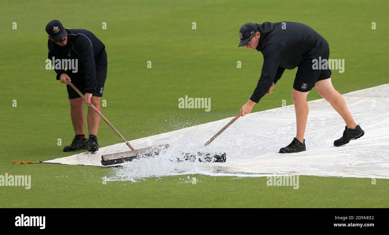 Ground staff sweep water off the covers during a rain delay in the ...