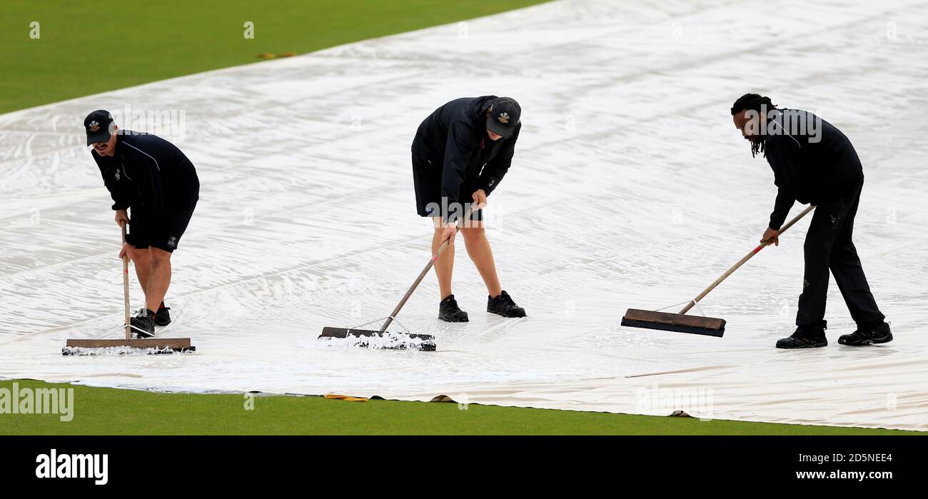 Ground staff sweep water off the covers during a rain delay in the ...