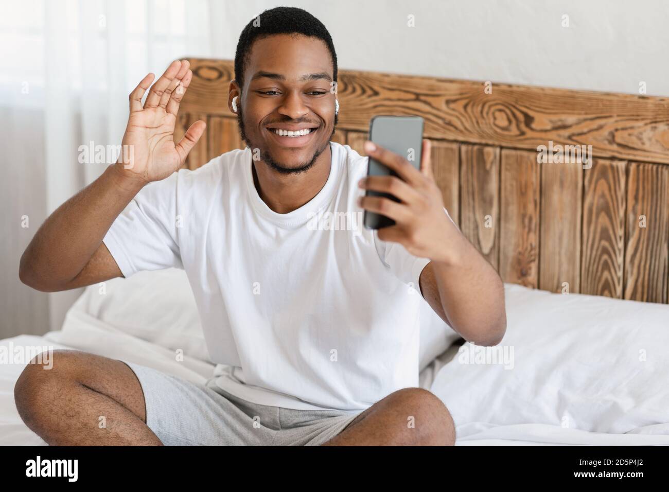 Cheerful African Guy Making Video Call On Cellphone In Bedroom Stock ...