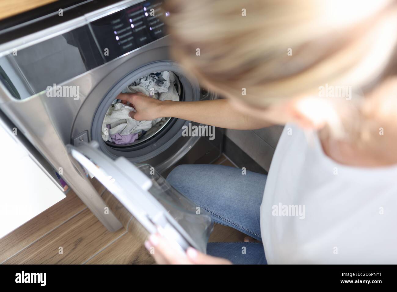Woman folds clothes into the washing machine Stock Photo - Alamy