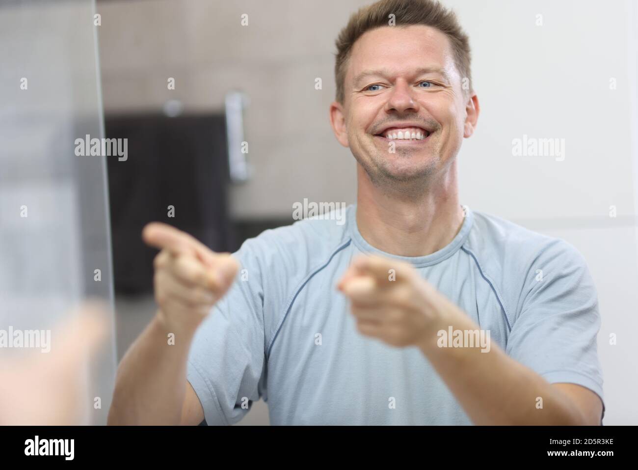 Smiling man in front of mirror points at his reflection Stock Photo - Alamy