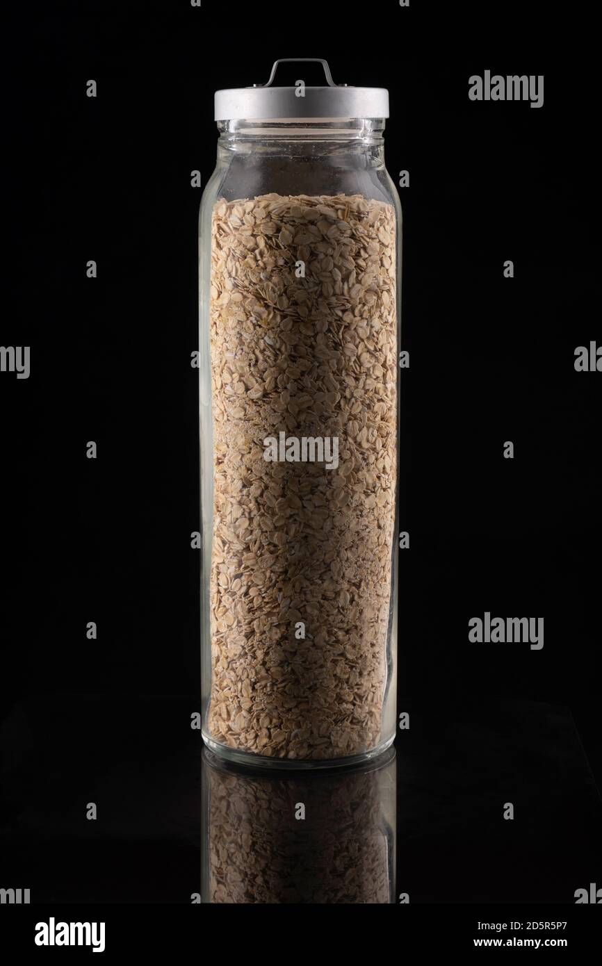 Oatmeal grain in glass bottle on black background. Storage of food ...
