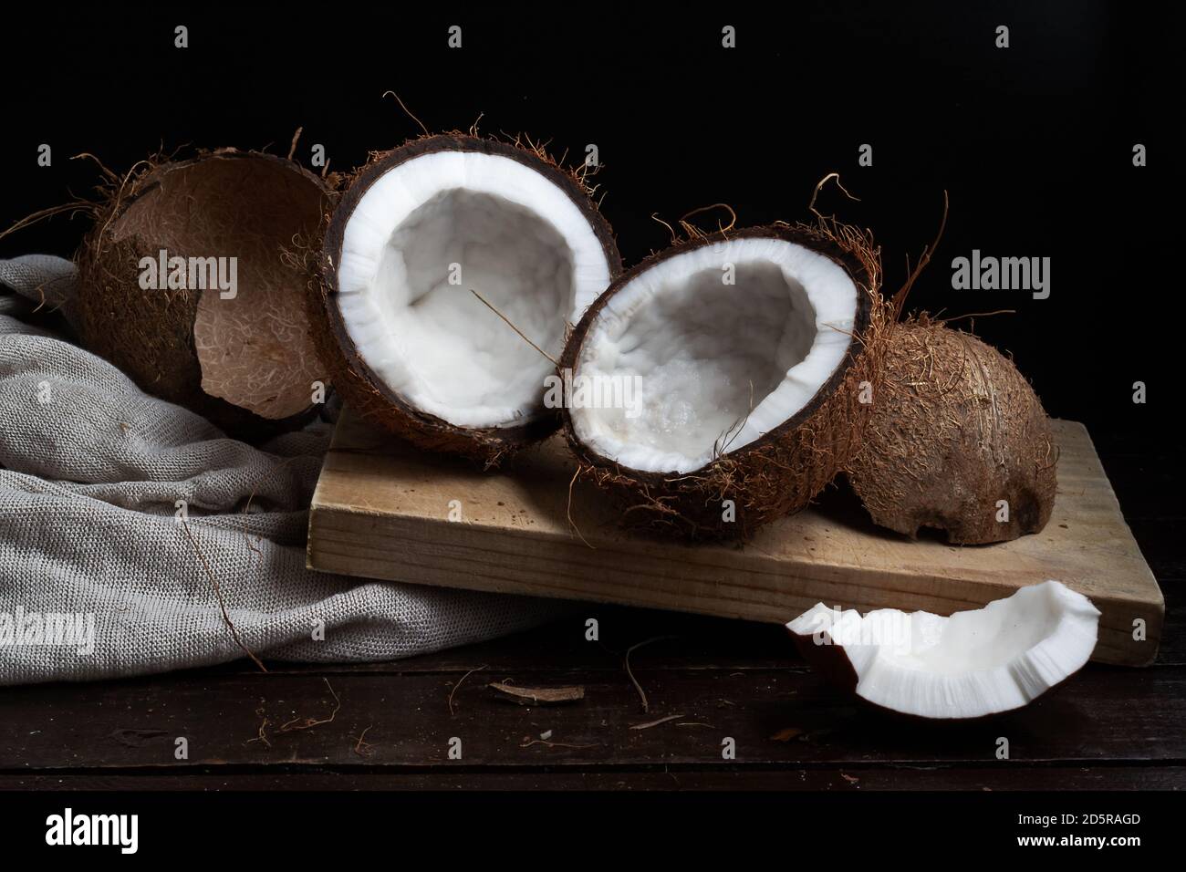 Coconut cut in half, fruit on the board isolated on the black ...