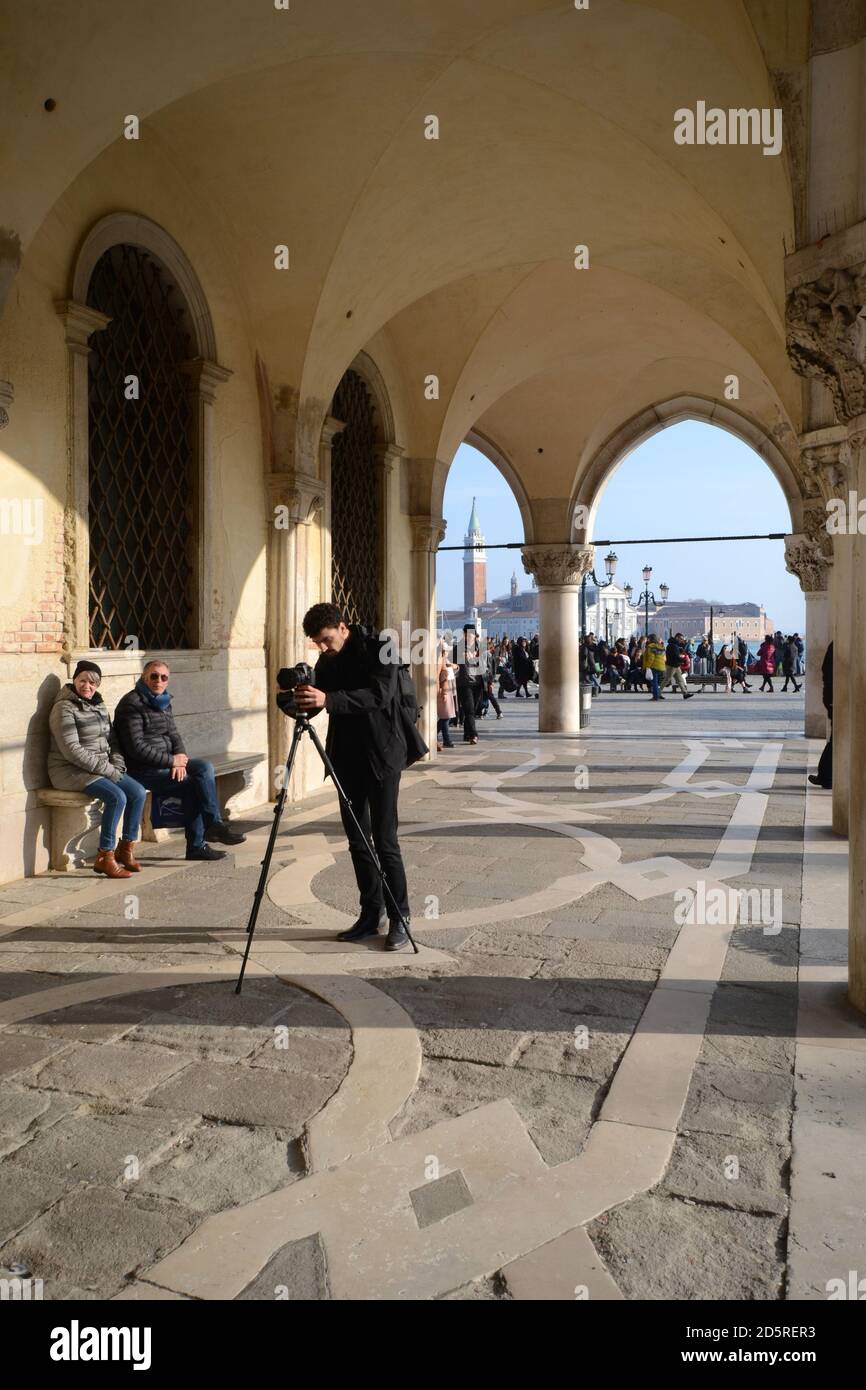 photographer places the camera on the tripod under a portico in piazza ...