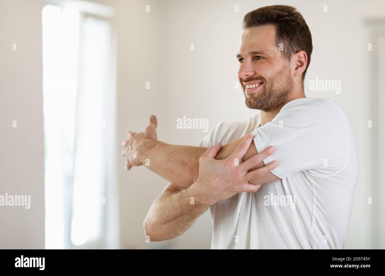 Happy Man Training At Home, Exercising Stretching Arms In Bedroom Stock ...