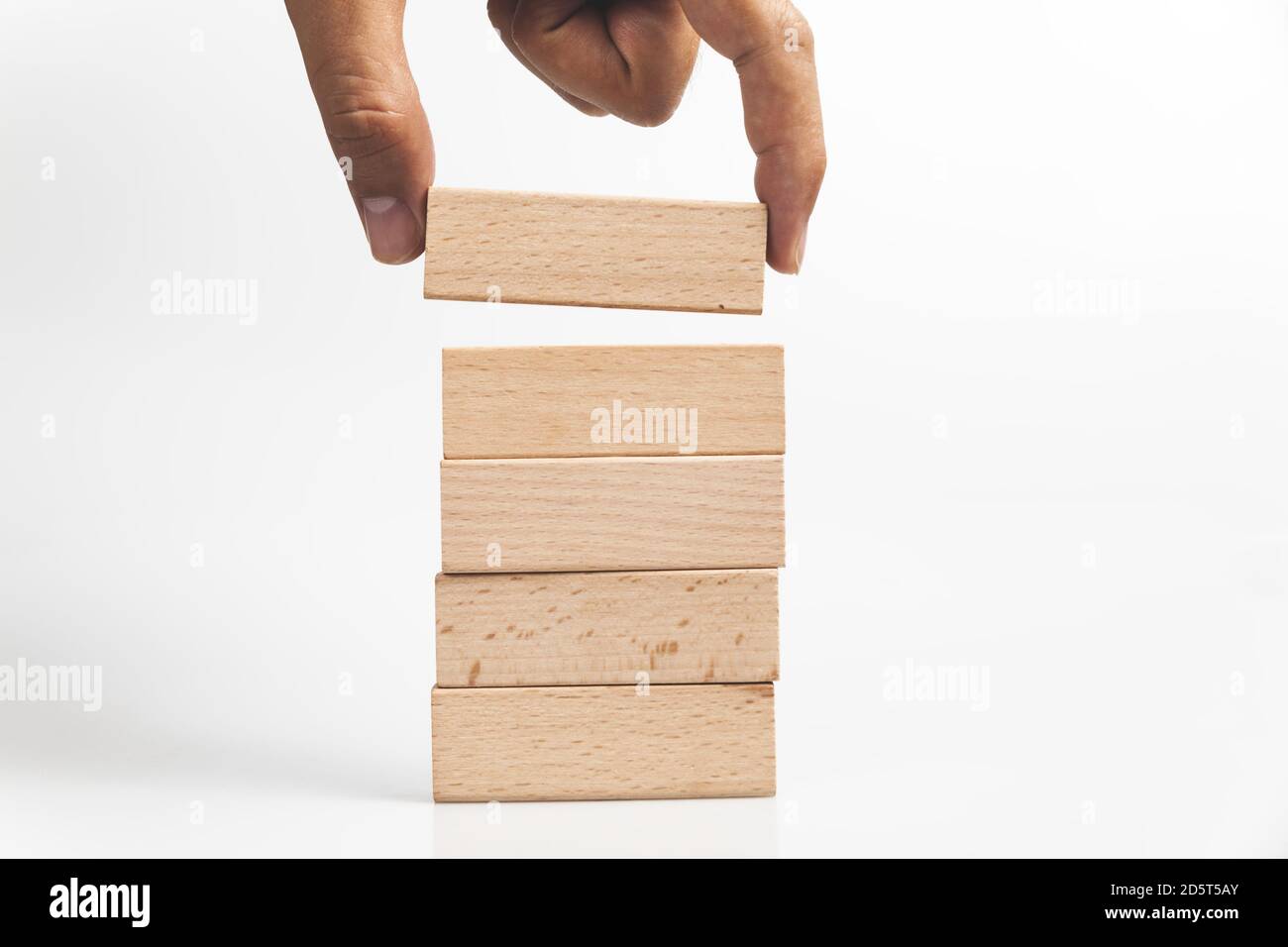 Closeup shot of a human hand putting wooden blocks on the stack of wooden blocks Stock Photo - Alamy