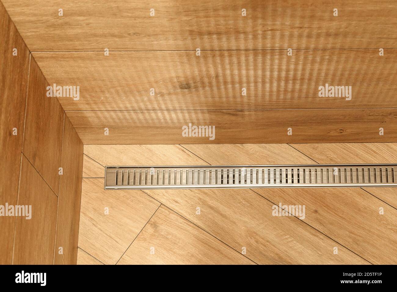 drain in the form of a mesh in the bathroom with wood-effect tiles ...