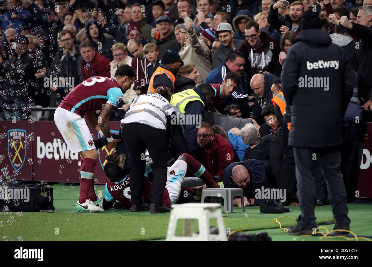 Fans fall from the stands over the advertising boards as they celebrate ...