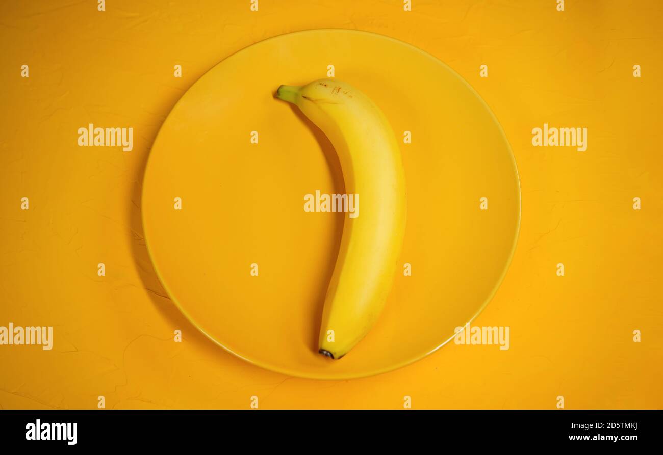 Banana on a yellow plate. Yellow banana on a yellow textured background ...
