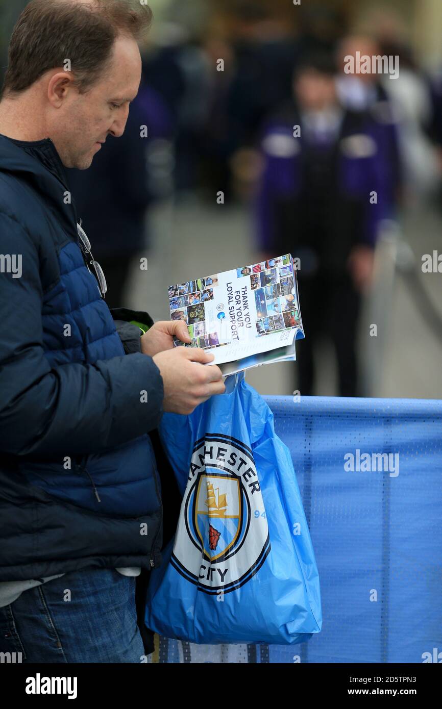A Manchester City fan reads the matchday program outside the stadium ...