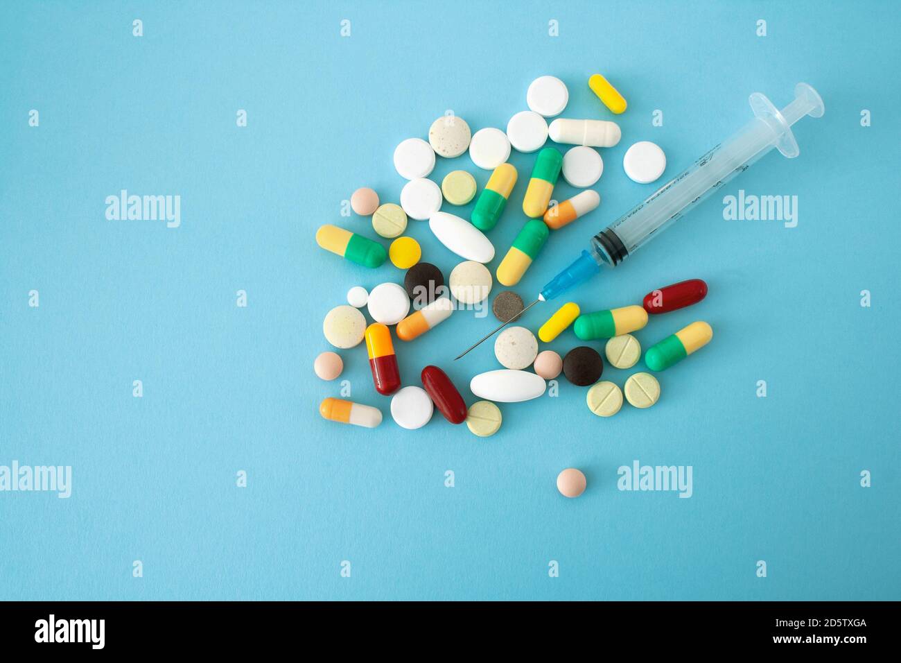 Multi-colored pills and capsules placed on a blue-green background with ...