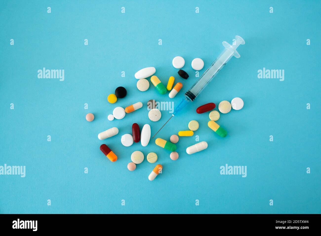 Multi-colored pills and capsules placed on a blue background with a ...