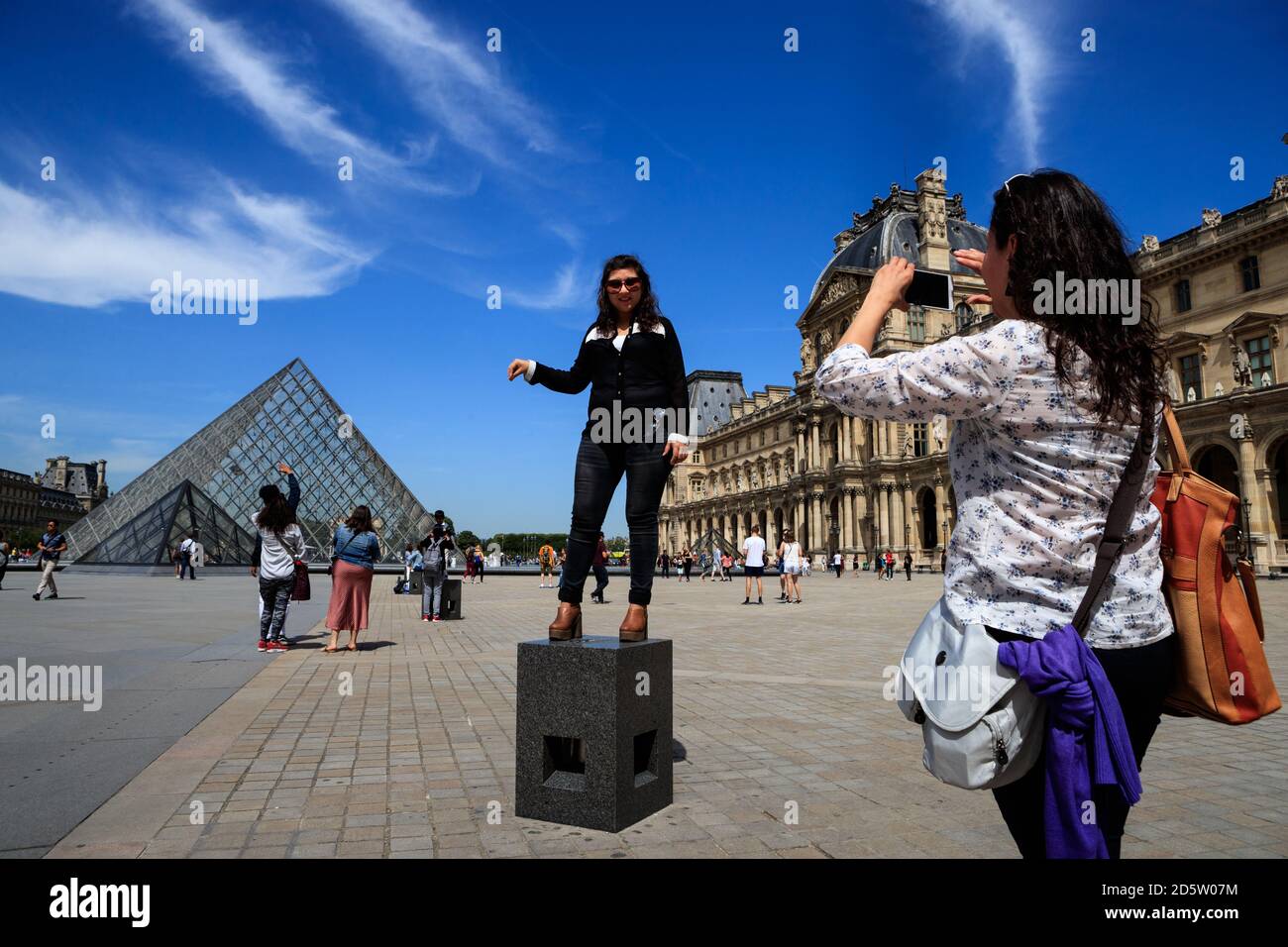 Tourists pose for photographs outside of The Louvre Palace, Paris Stock ...