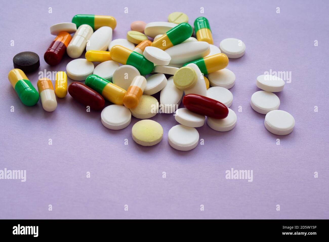 Colorful pills and capsules on a purple background, macroshot tablets ...