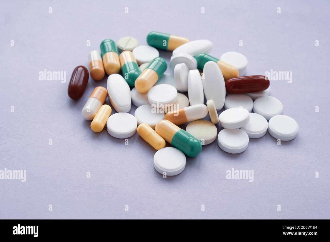 Colorful pills and capsules on a purple background, macroshot tablets ...