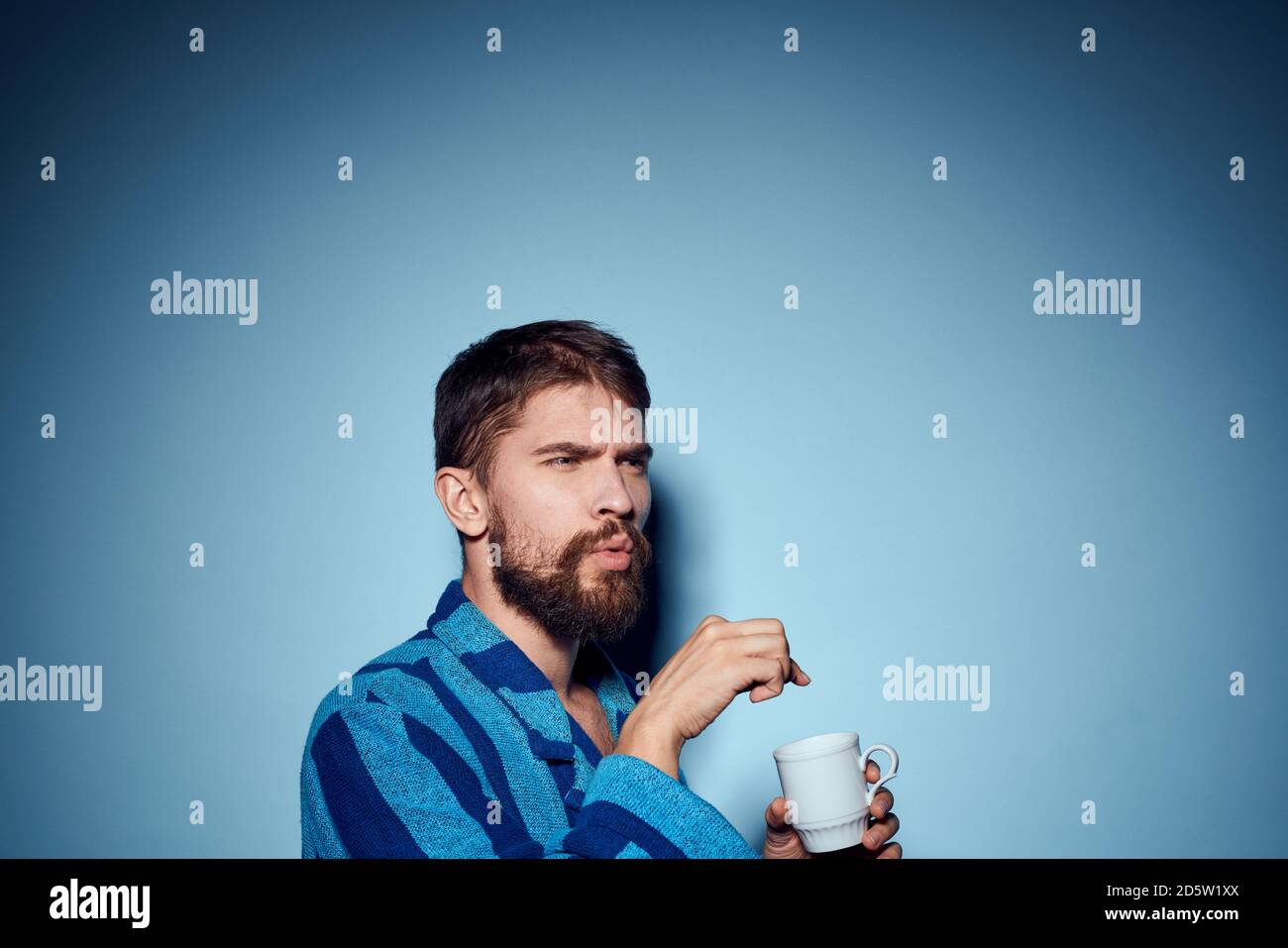 man in striped blue robe holding white cup in hand and emotions fun ...