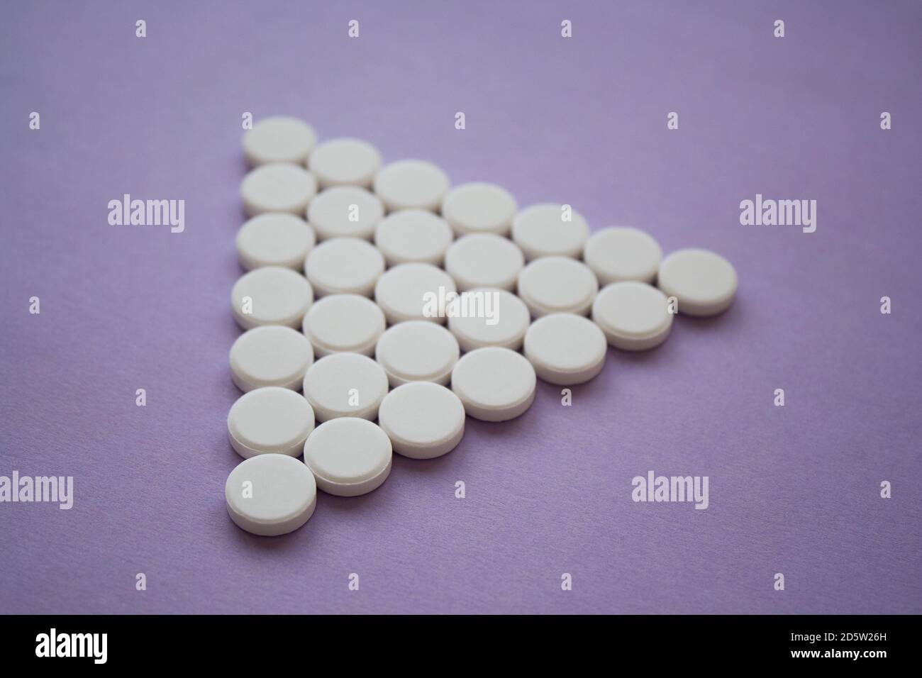 Round medicinal pills in the shape of a large triangle on a dark pink ...