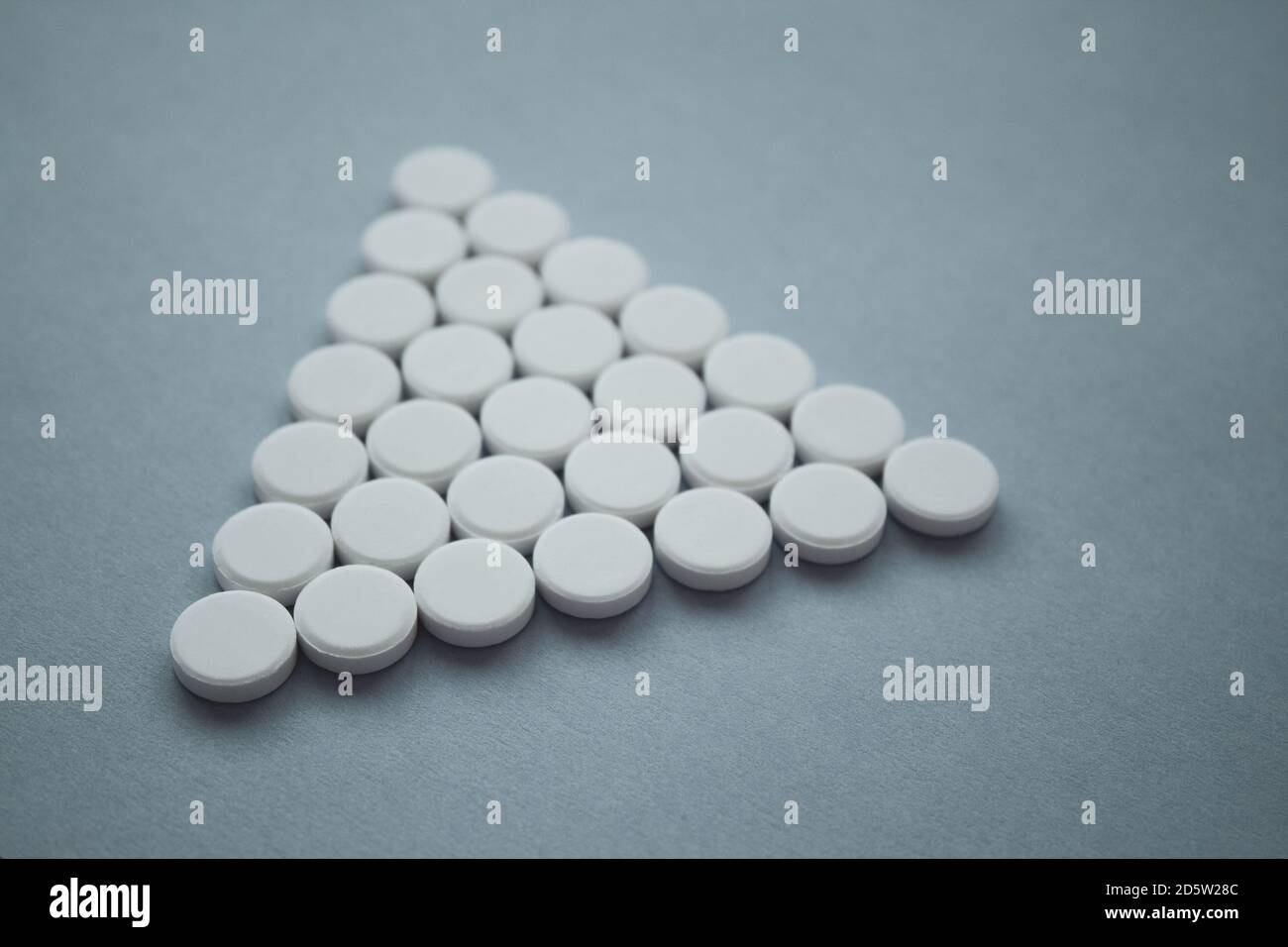 Round medicinal pills in the shape of a large triangle on a dark gray ...