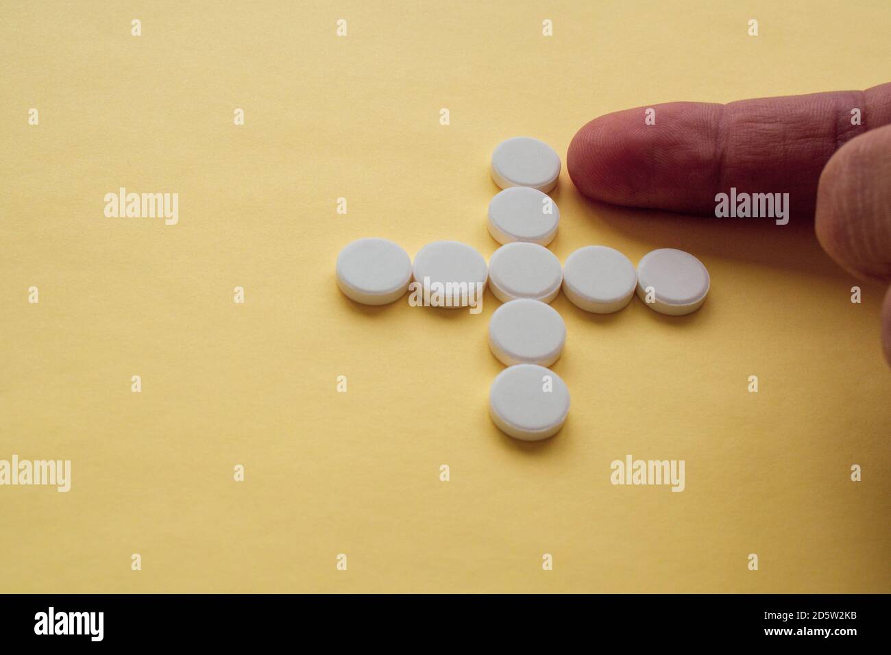 round white tablets in the shape of a cross on a yellow background ...