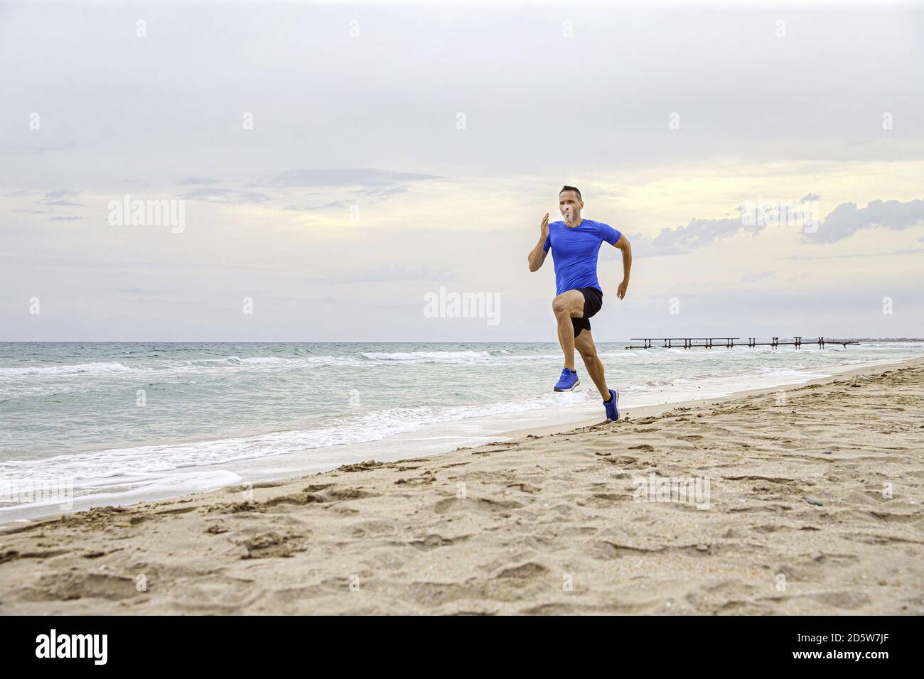 male runner running an evening training on sandy sea beach Stock Photo ...