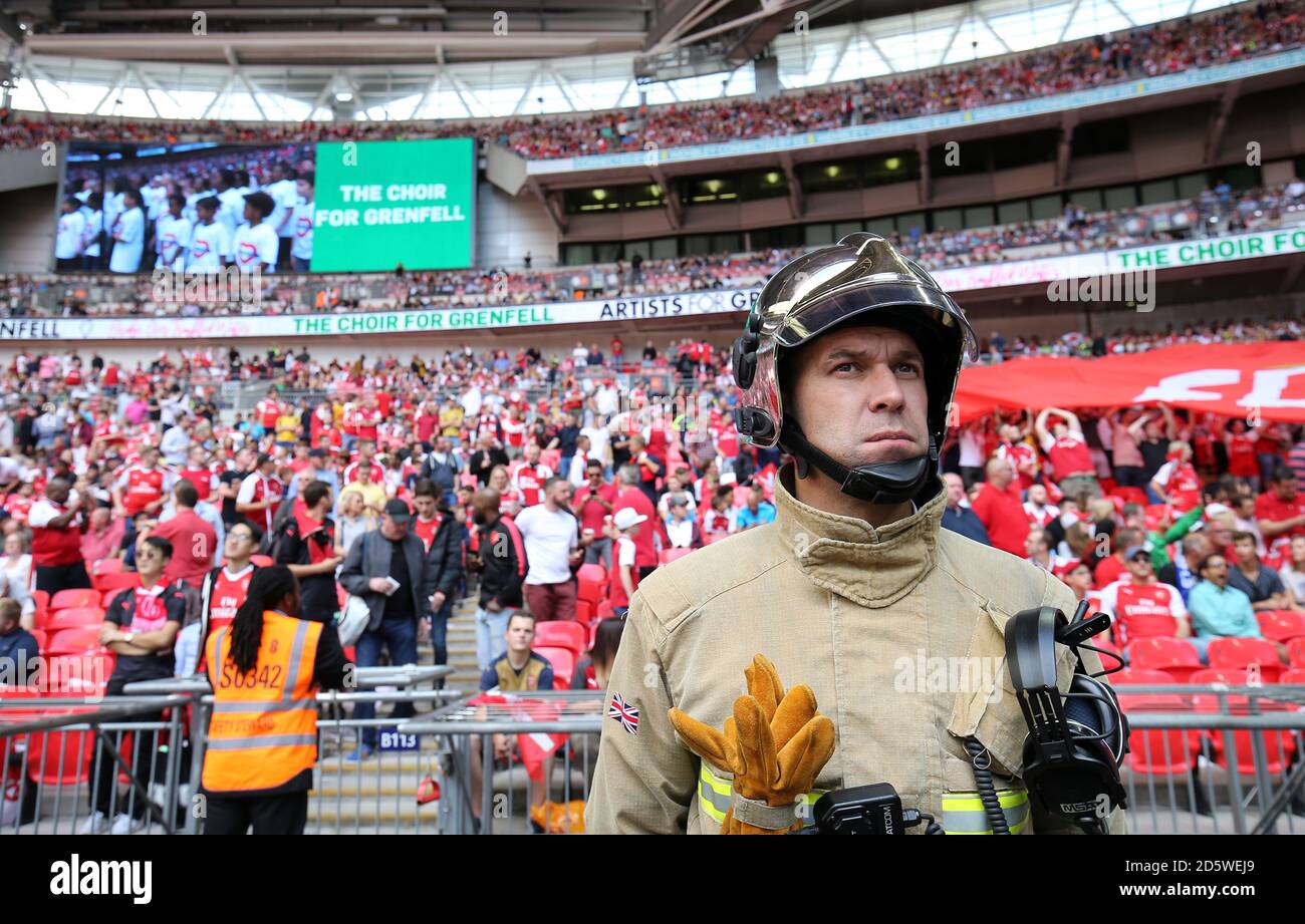A fireman stands with the crowd as The Choir For Grenfell sings before ...