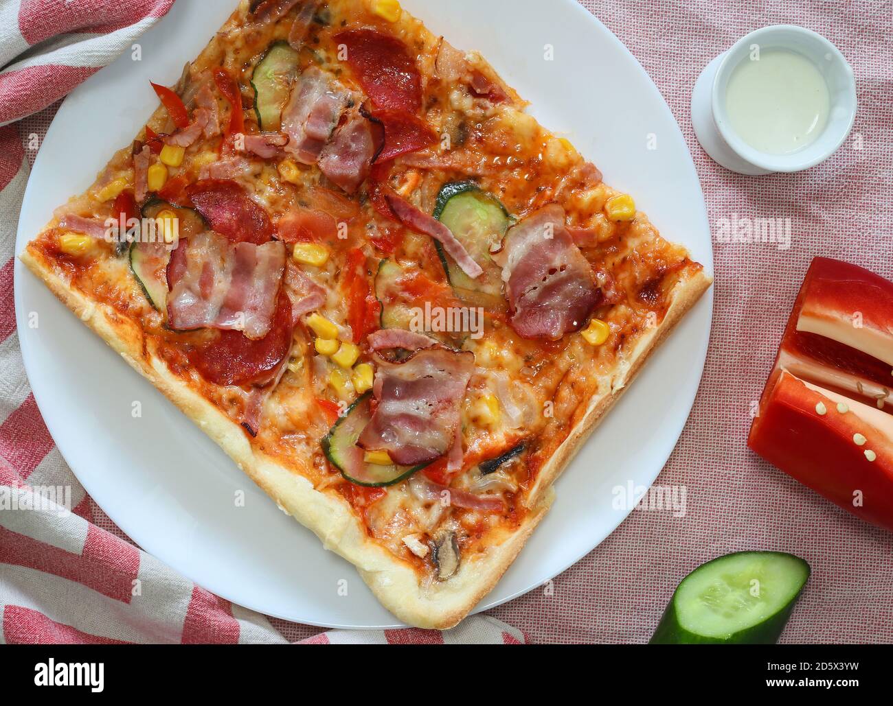 Rectangular piece of home made pizza with bacon, corn, salami, ham ...