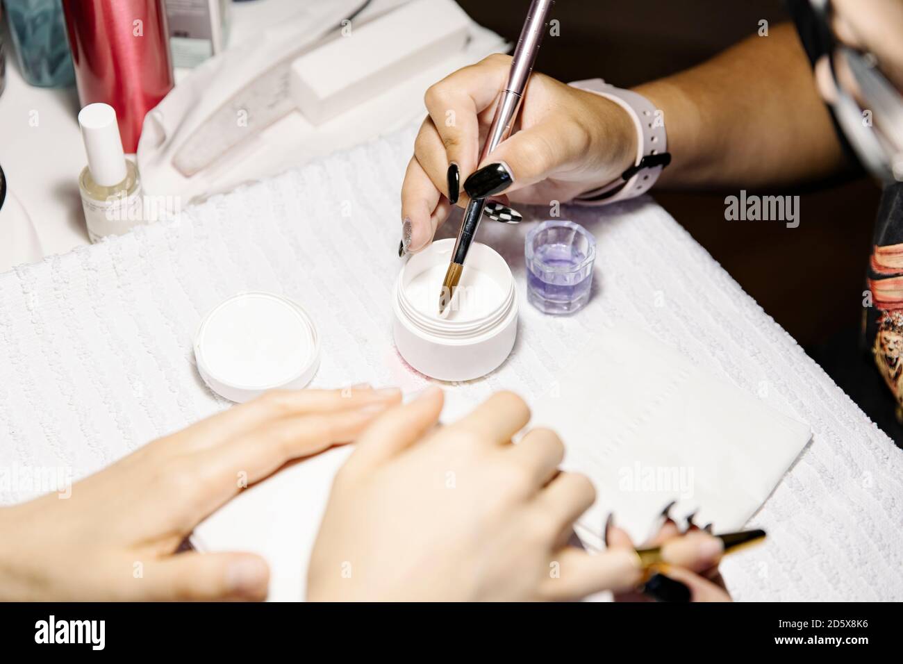 Crop nail artist taking white dye from jar while making French manicure ...