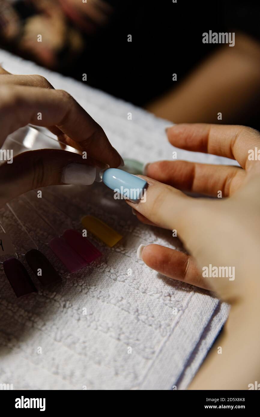 From above anonymous female selecting nails color over towel in salon ...