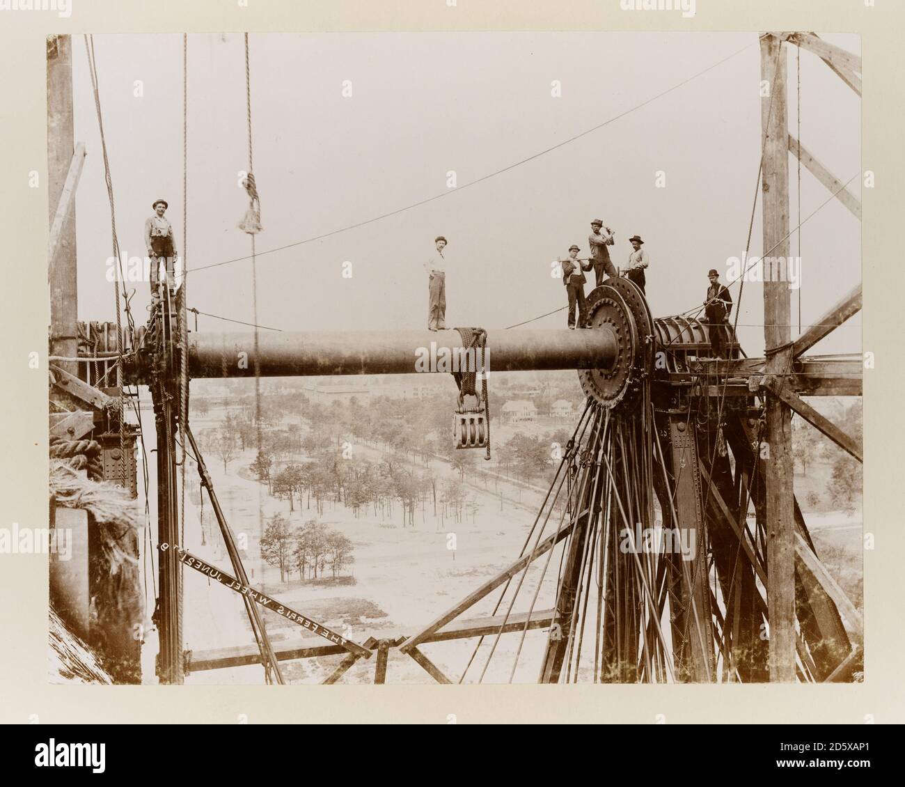View of workers standing atop the Ferris wheel axle during its ...