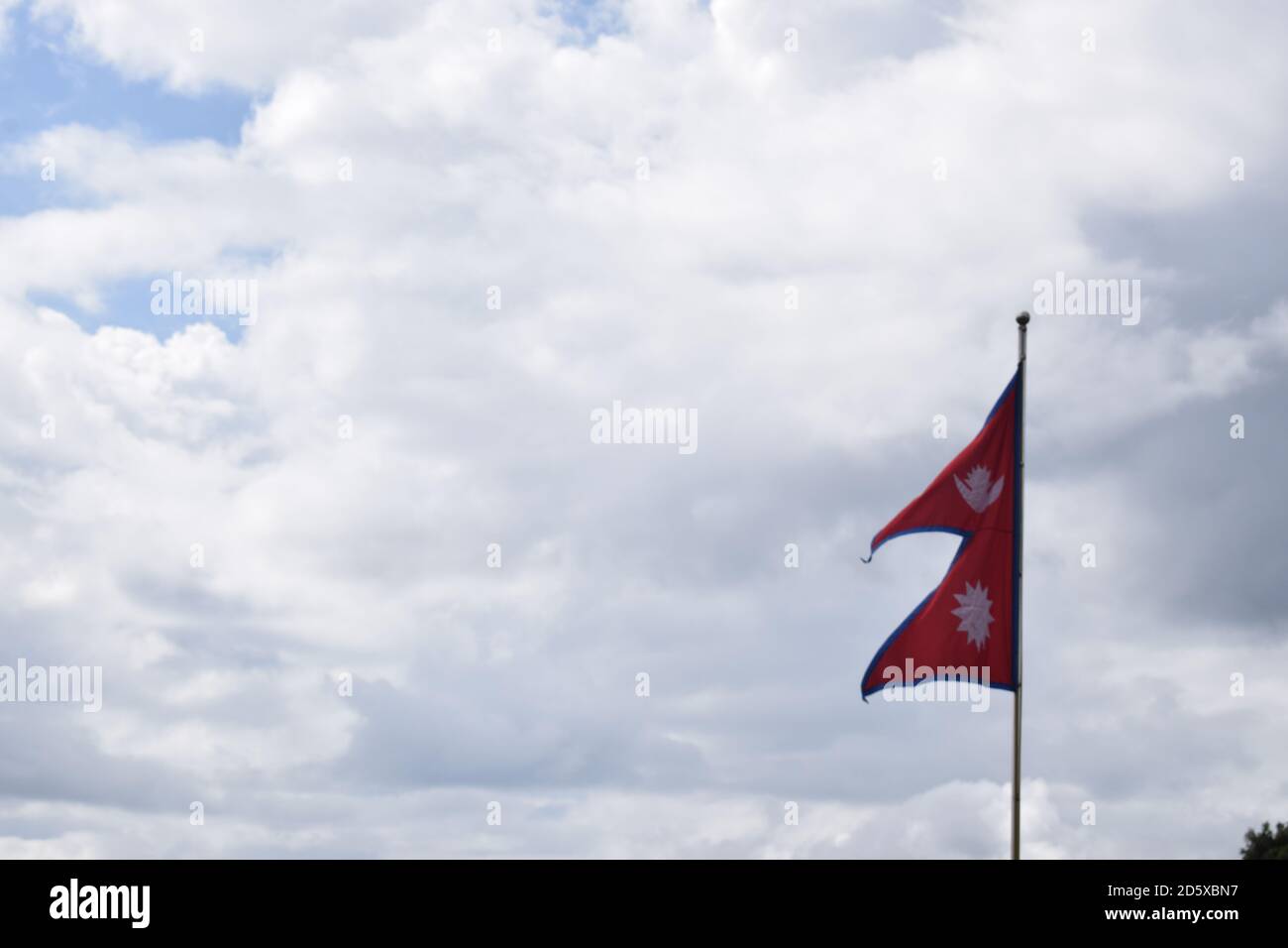 Nepal's National Flag ( Chandra Surya Flag ) among the blue cloudy sky ...