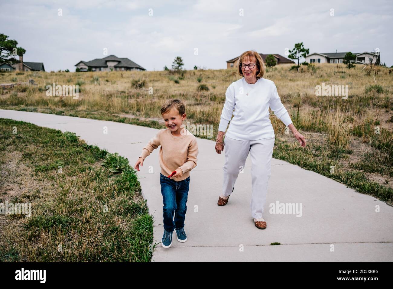 Grandmother chasing smiling grandson outside on a cloudy day Stock ...