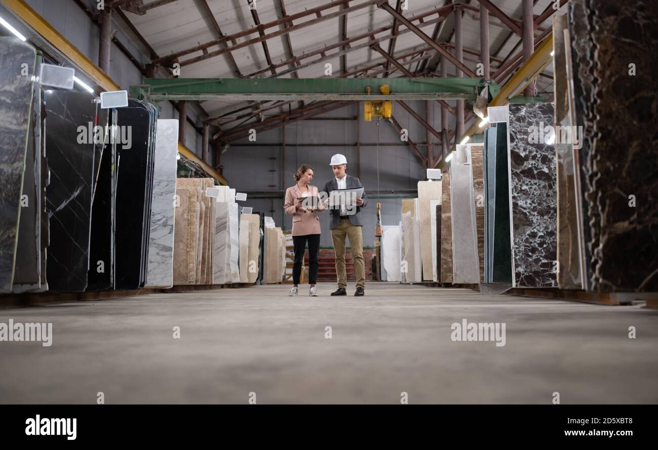 Full body male and female architects discussing drafts in marble ...