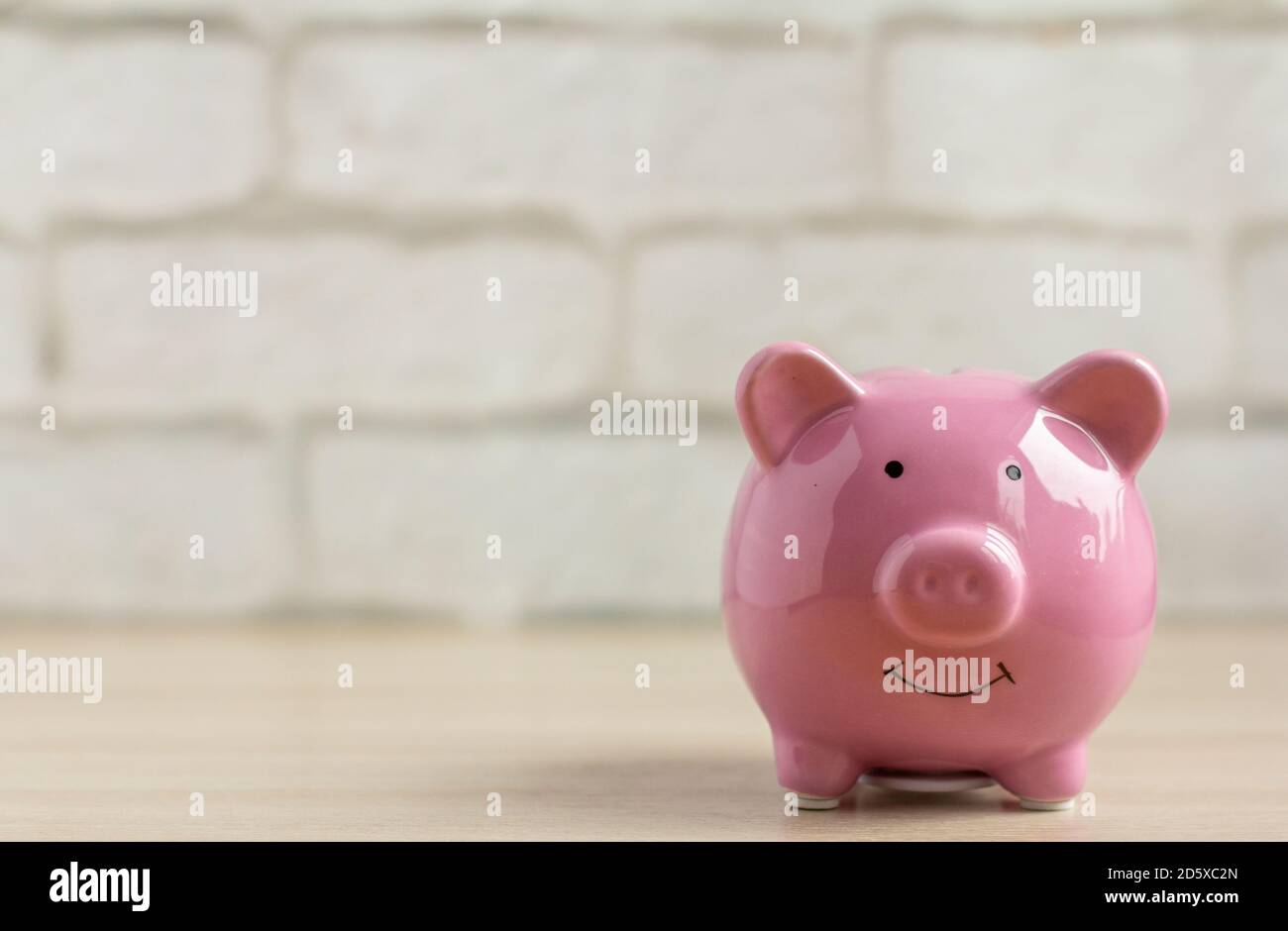 Pink piggy Bank on a table or shelf against a light brick wall Stock ...